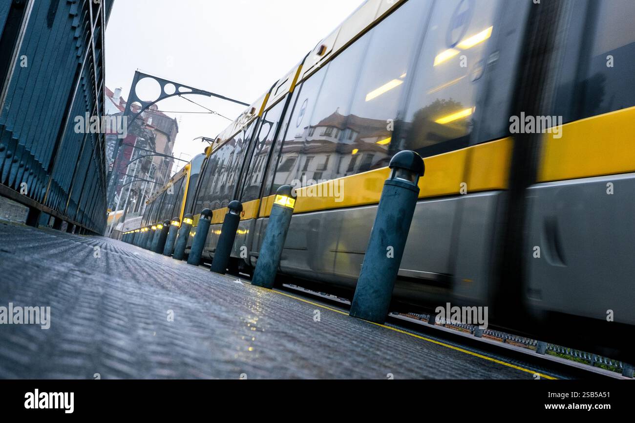 A yellow metro train travels on the iconic Dom Luis I Bridge in Porto ...