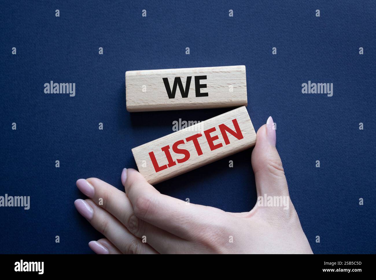 We listen symbol. Wooden blocks with words We listen. Businessman hand ...