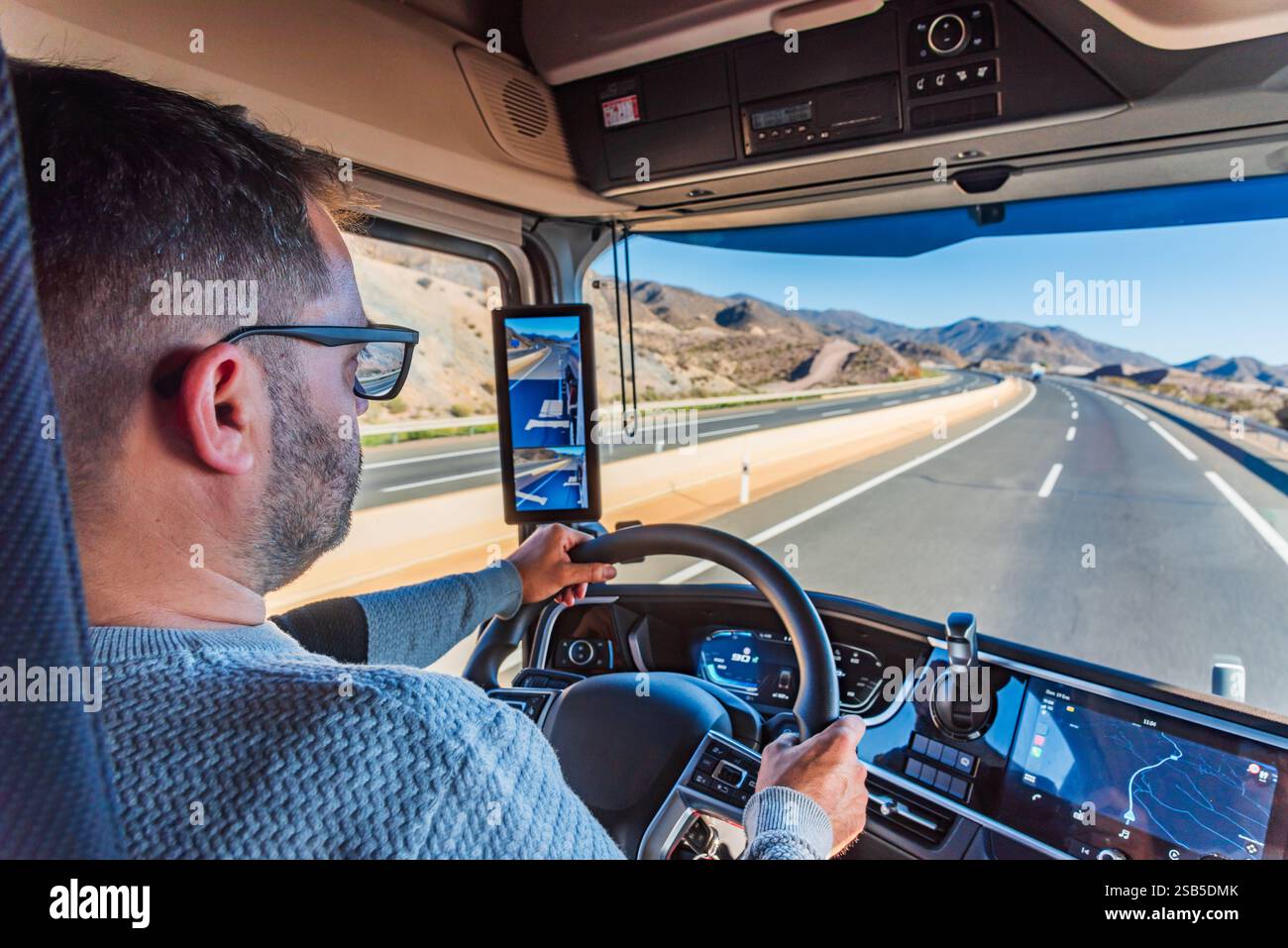 Truck driver operating a heavy vehicle on the highway, attentive to ...