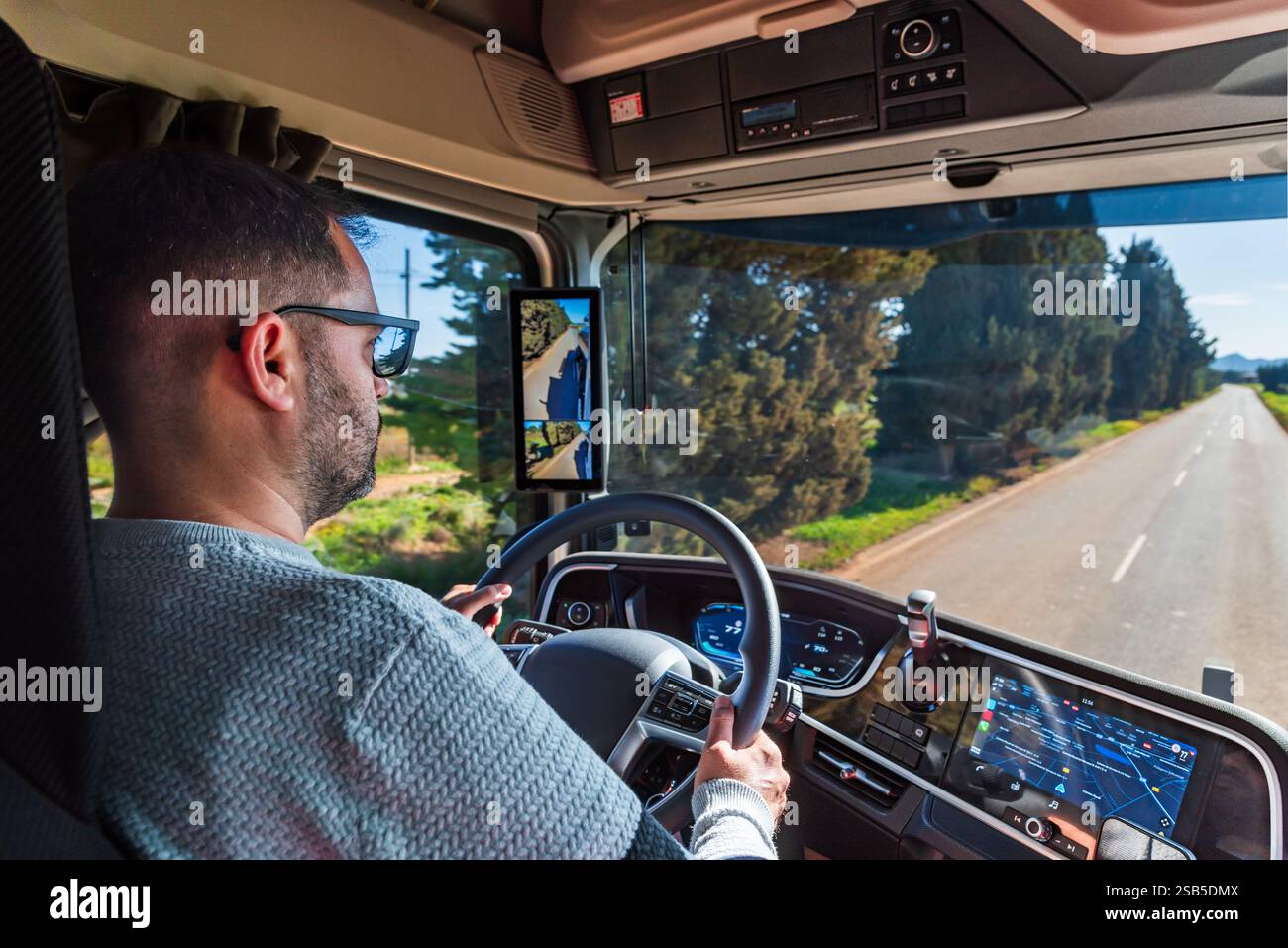 Truck driver seen from inside the cabin driving on a conventional two ...