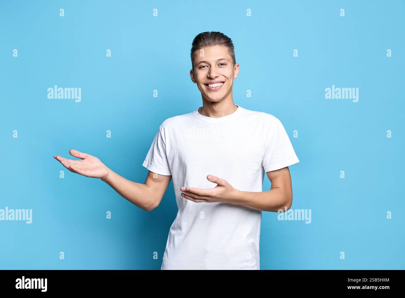 Happy man welcoming friends or guests on light blue background Stock ...