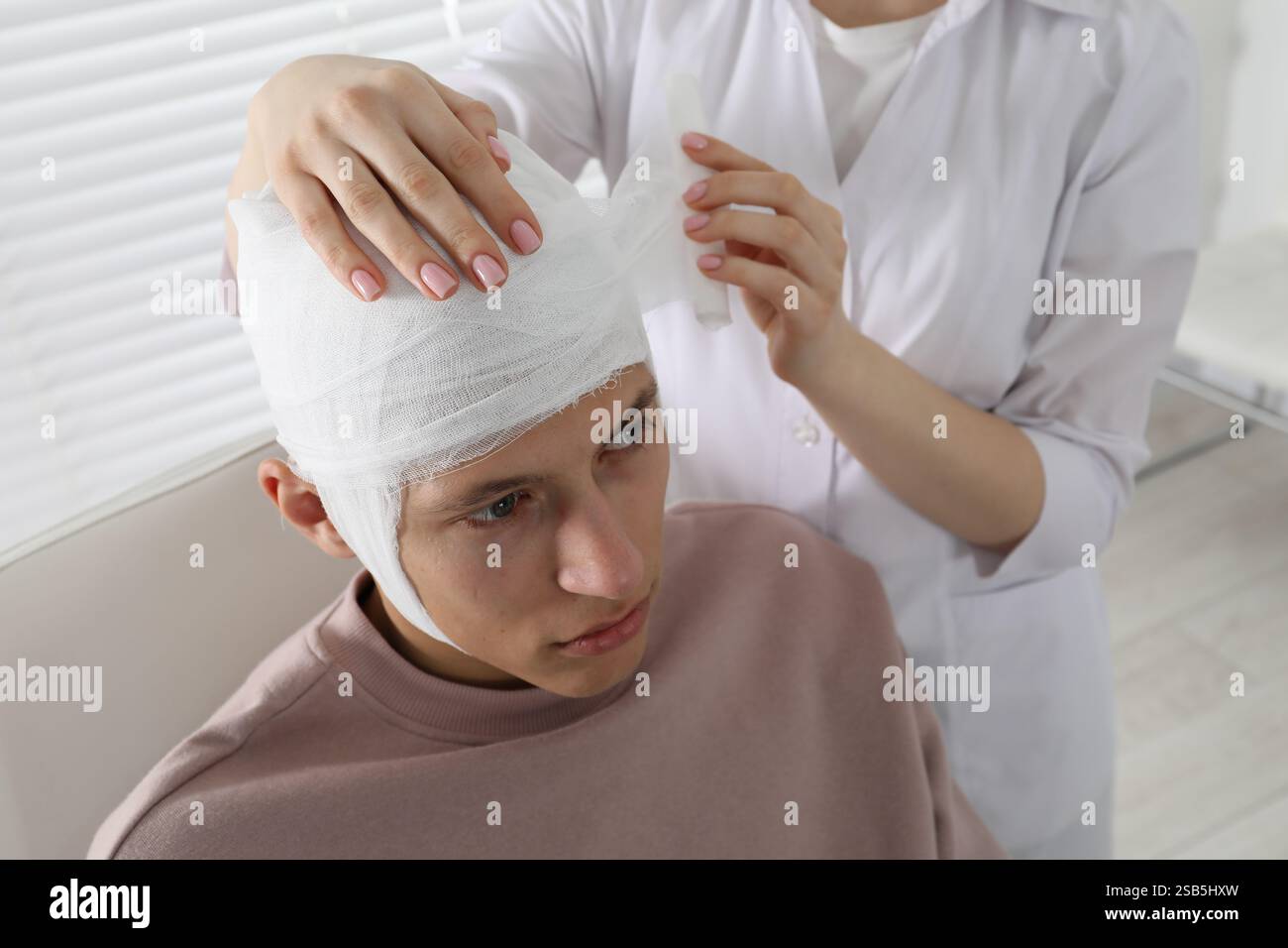 Doctor bandaging patient's head in clinic, closeup Stock Photo - Alamy