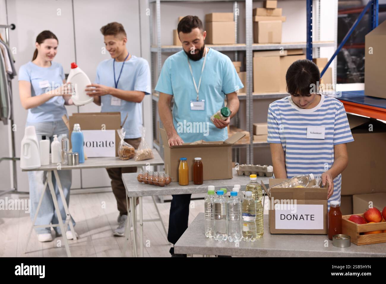 Volunteers packing donation goods at tables indoors Stock Photo - Alamy