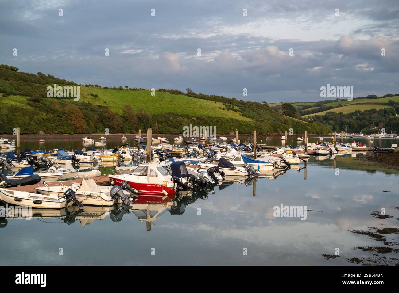Small boats mored to a jetty at Salcombe yacht club, with reflections ...