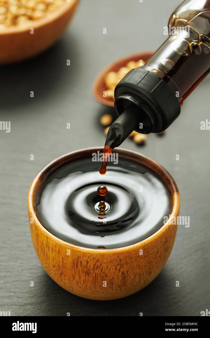 closeup soy sauce pouring from bottle in bowl with splash and drop and ...