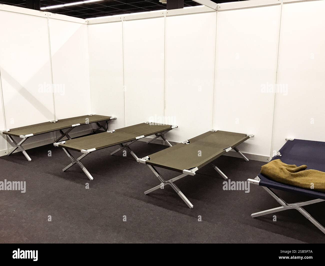 Row of beds are lined up against a wall, refugee camp in Cologne. The ...