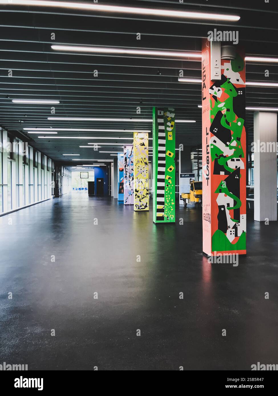 Long hallway with colorful pillars and a black floor. The pillars are ...