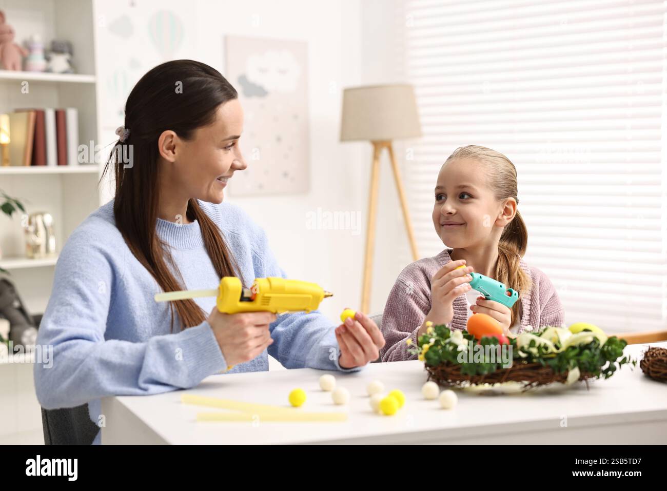 Mother and daughter with hot glue guns creating Easter composition at ...