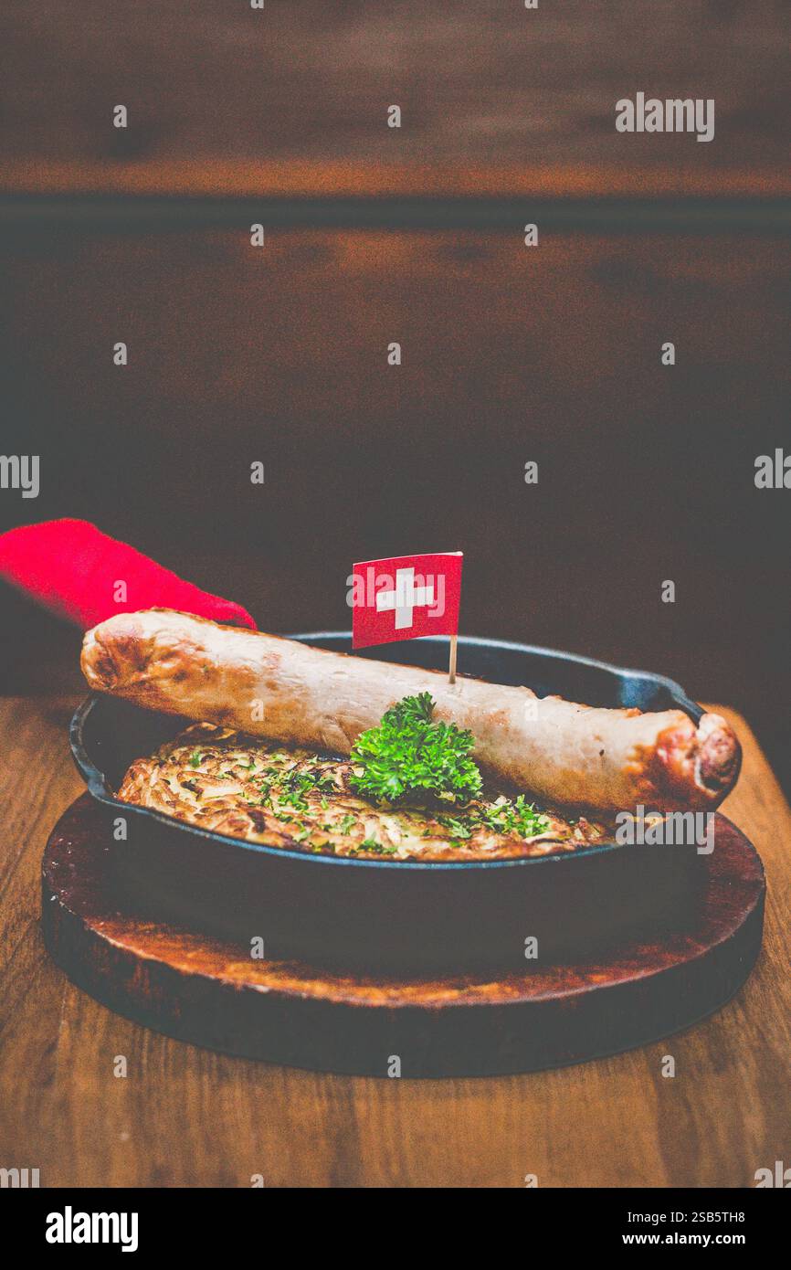 Rosti with Veal Sausage served in a cast iron pan with a Swiss flag on ...