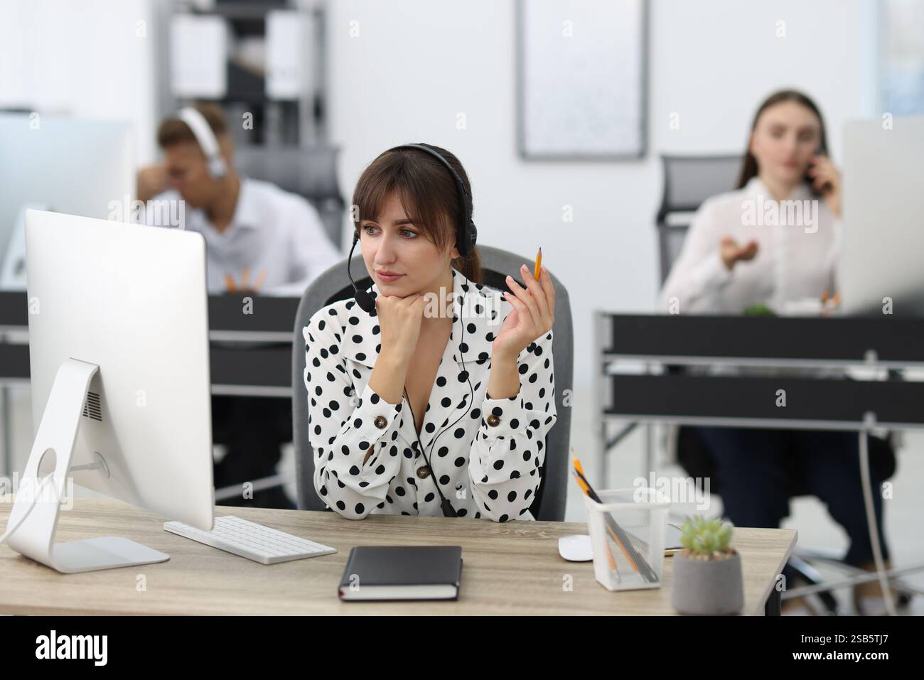 Saleswoman talking to client via headset at desk in office Stock Photo ...