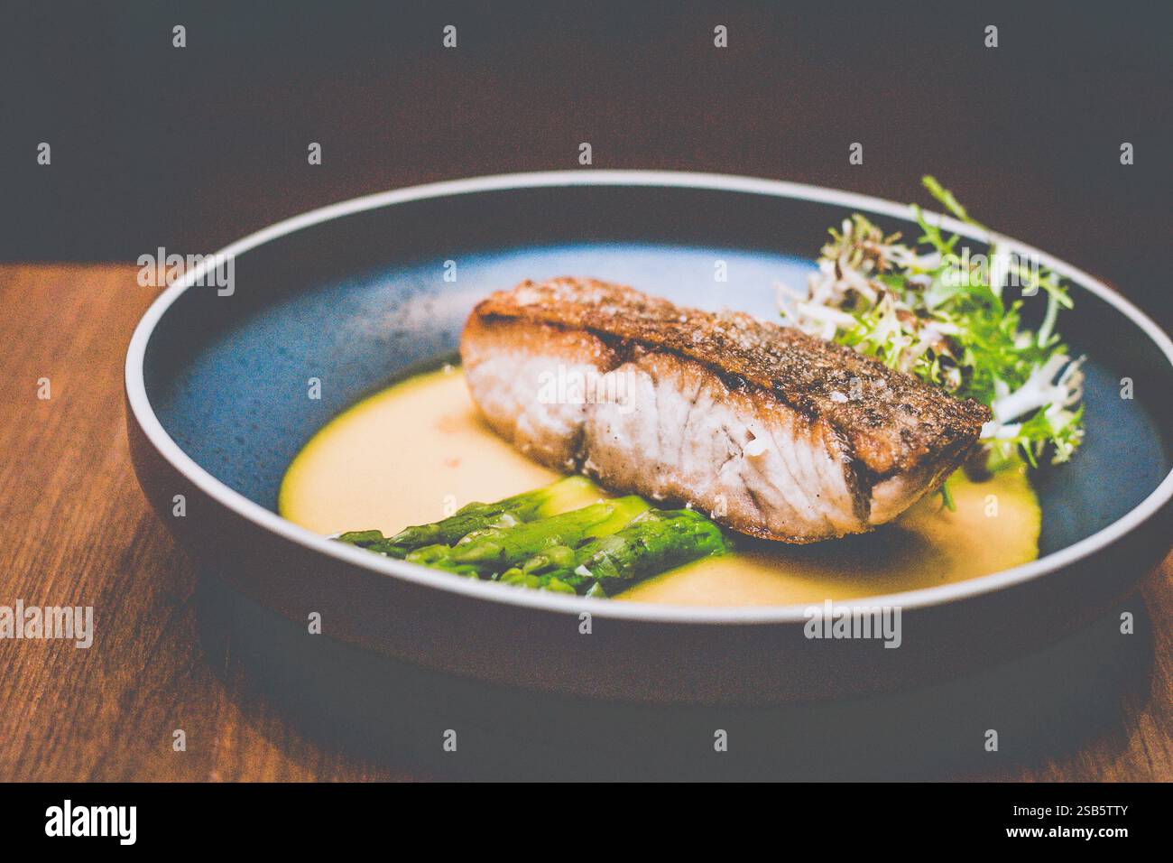 pan fried Sea Bass fillet with saffron sauce and green asparagus in a ...