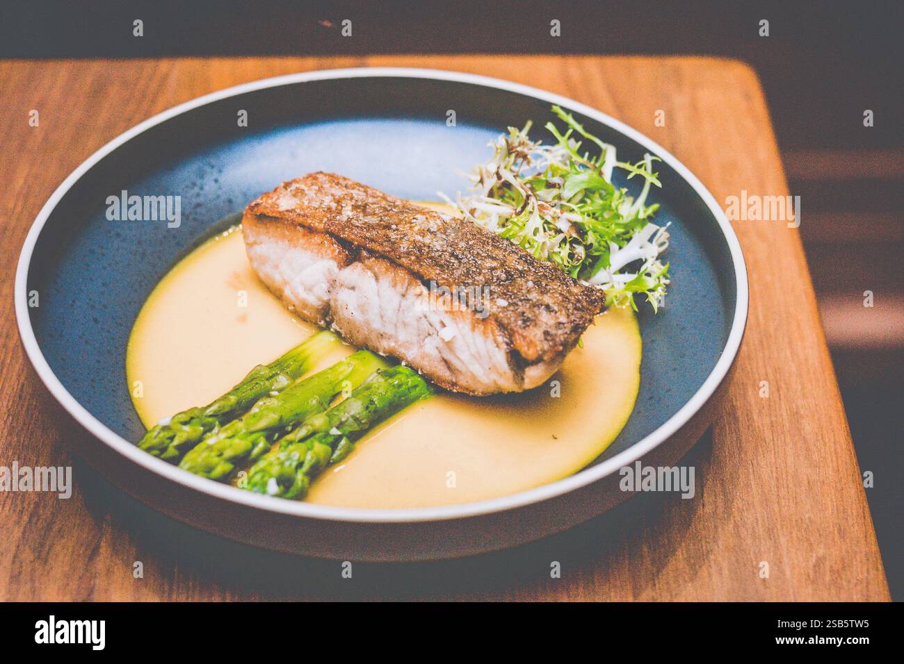 pan fried Sea Bass fillet with saffron sauce and green asparagus in a ...