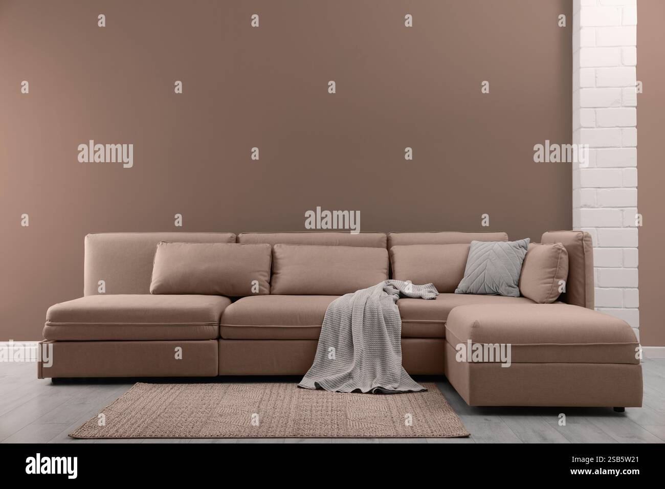 Stylish interior in mocha mousse shade. Large sofa and wall in trendy ...