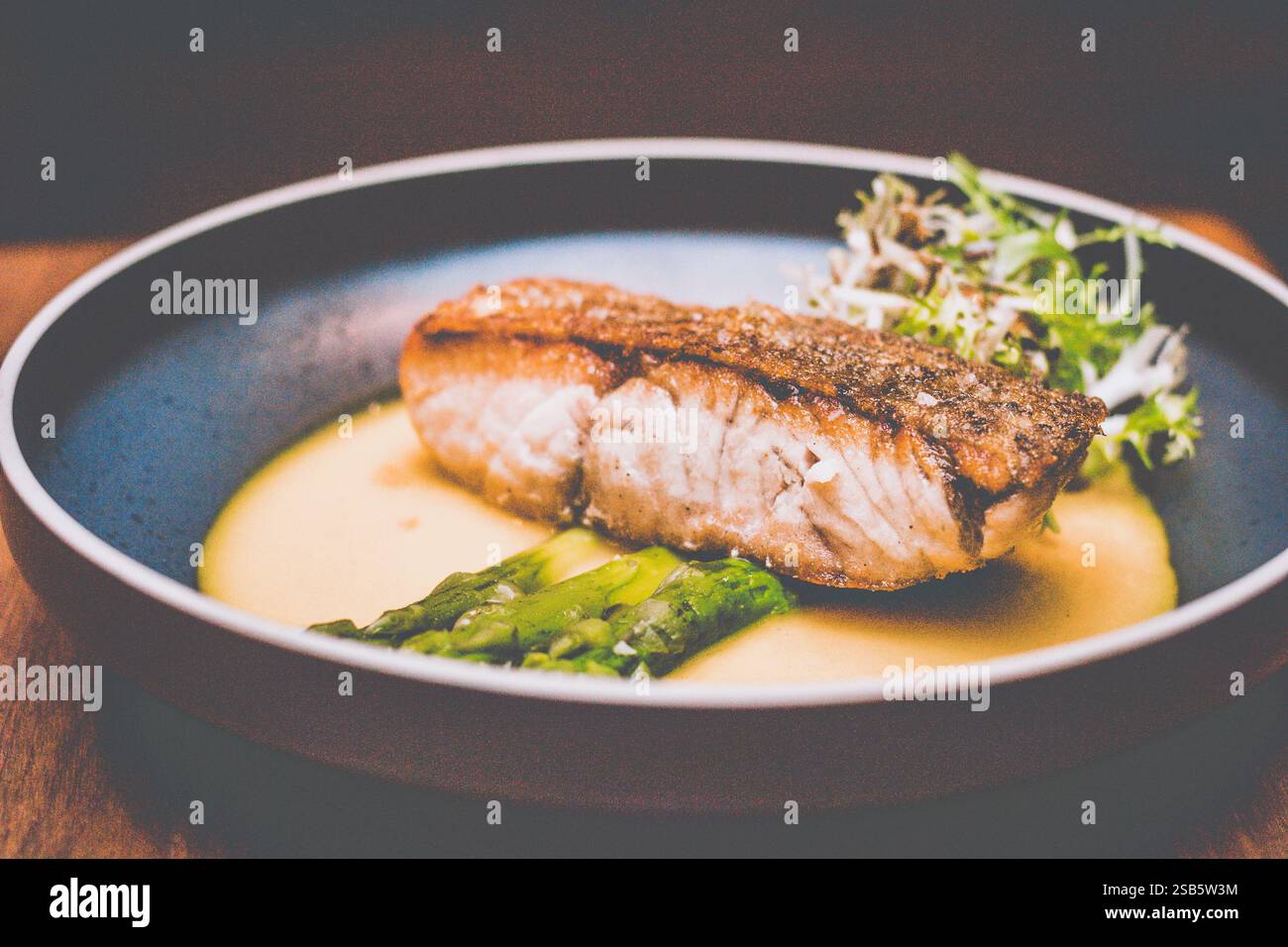 pan fried Sea Bass fillet with saffron sauce and green asparagus in a ...