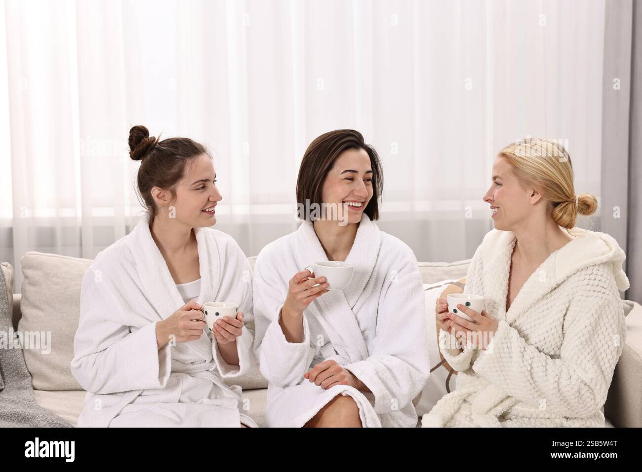 Beautiful women having tea on sofa in spa Stock Photo - Alamy