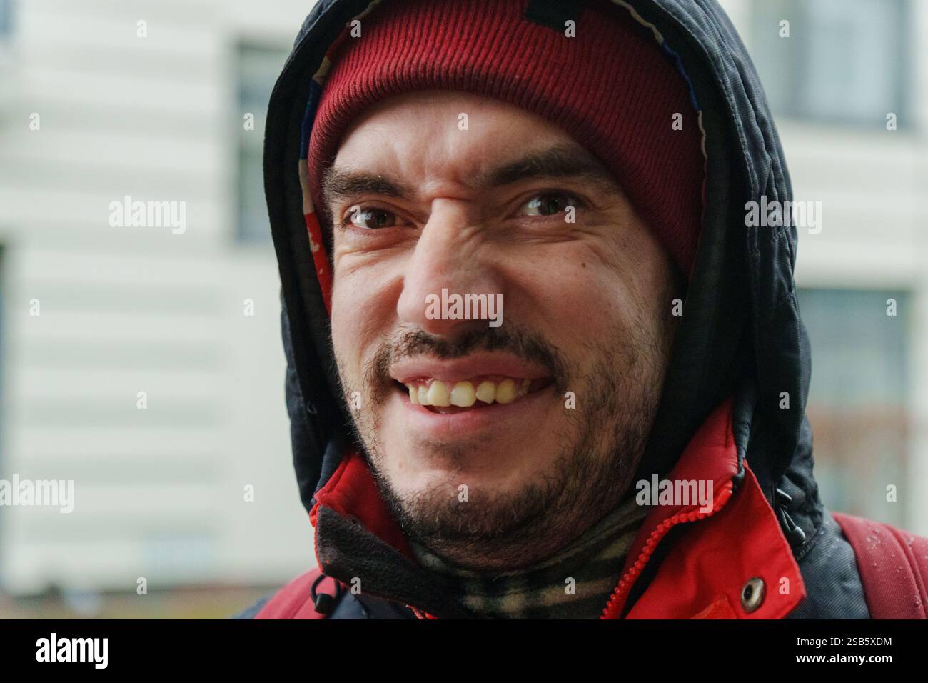 A cheerful man bundled up in a red jacket smiles warmly on a chilly day ...