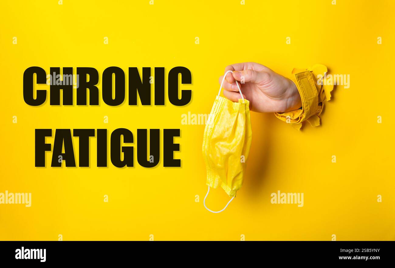 Person holding a yellow mask with the words Chronic Fatigue written ...