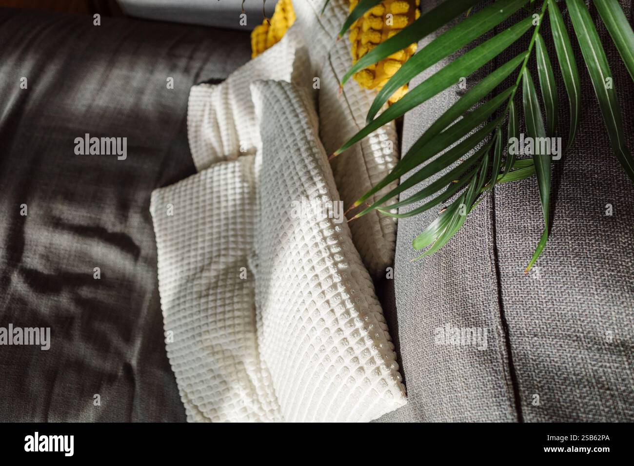 A soft white waffle-textured blanket draped over a grey fabric sofa ...