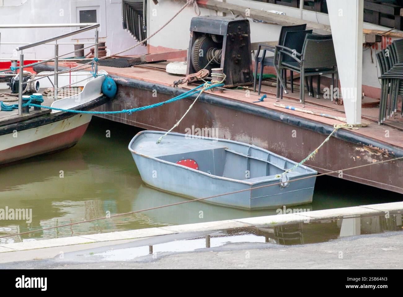 a small boat moored at the quayside. The boat is gray in color and has ...