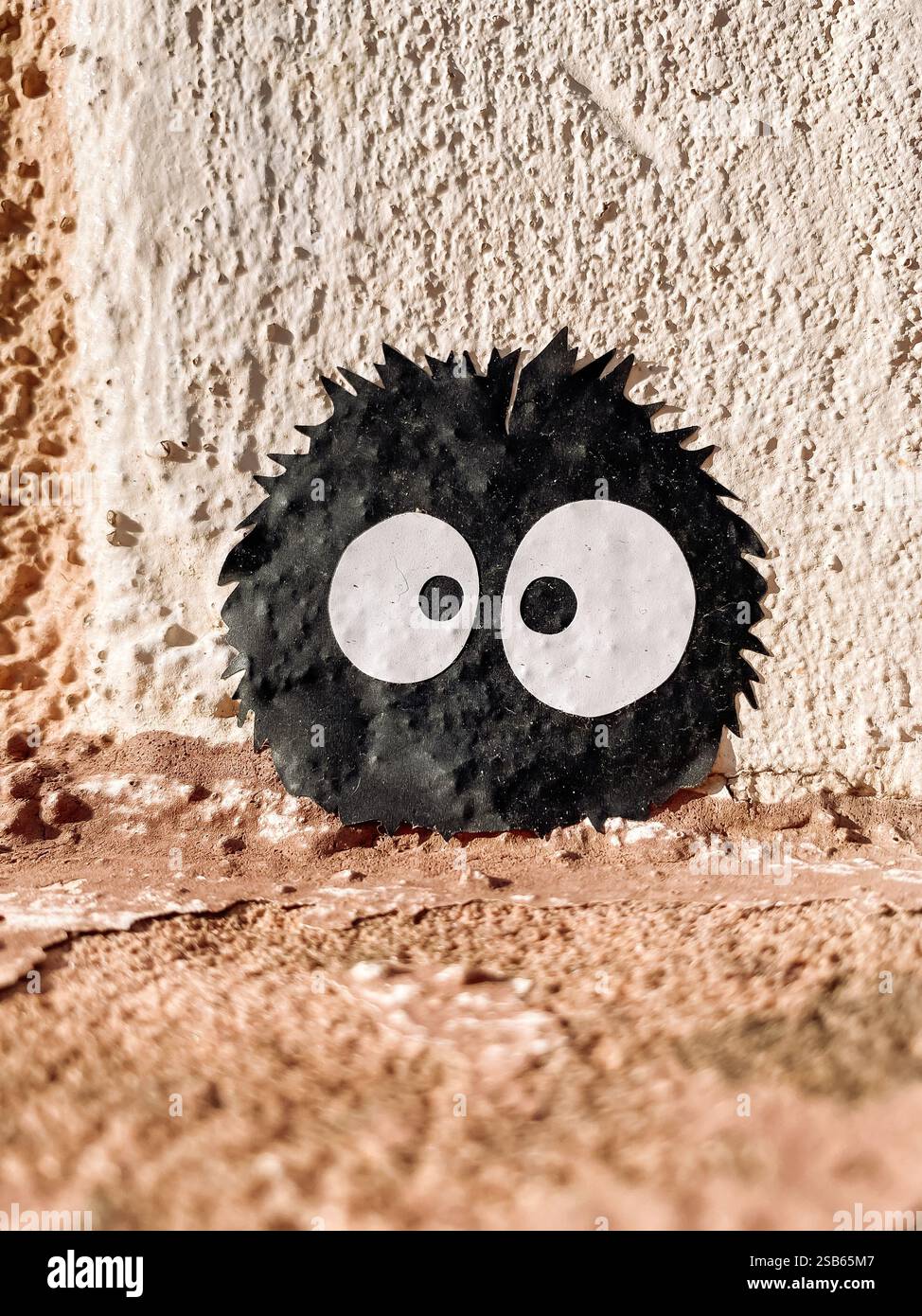 Small black and white creature with big eyes is sitting on a wall. The ...