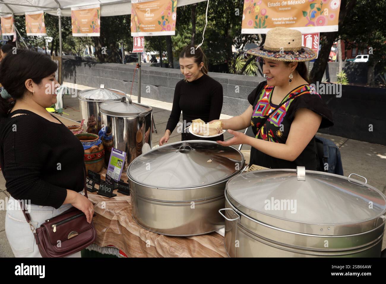 Non Exclusive: A vendor offers a tamale to a person at the first Tamale ...