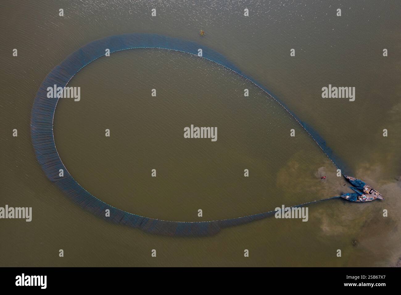 Aerial view of fishermen casting a giant fishing net in the Brahmaputra ...