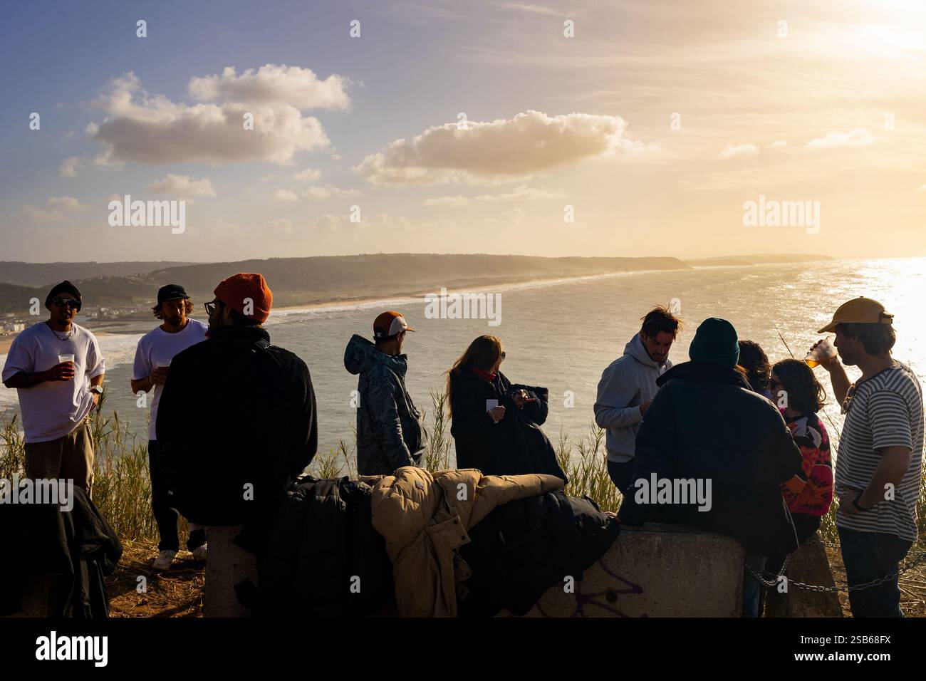 A gourp of people enjoys the sunset near Nazaré lighthouse. Hundreds of ...