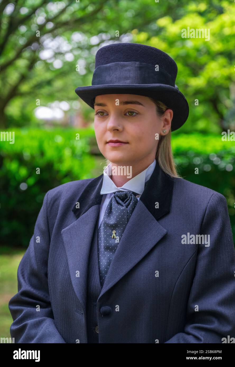 A young pretty lady funeral director in traditional attire with top hat ...