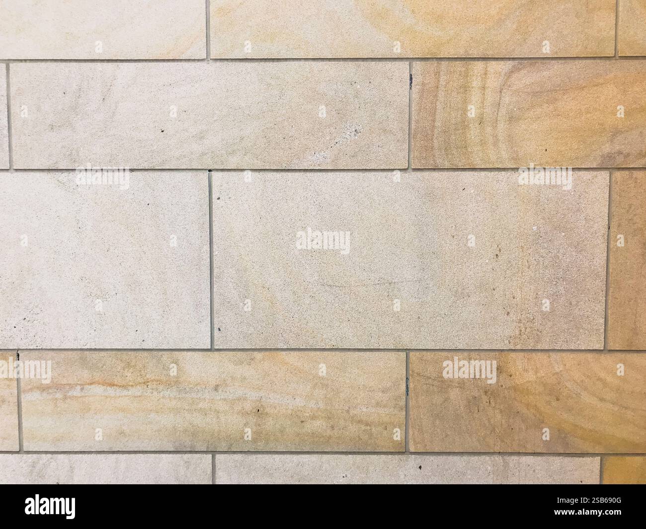 The wall is made of tan bricks and has a white border. The bricks are ...