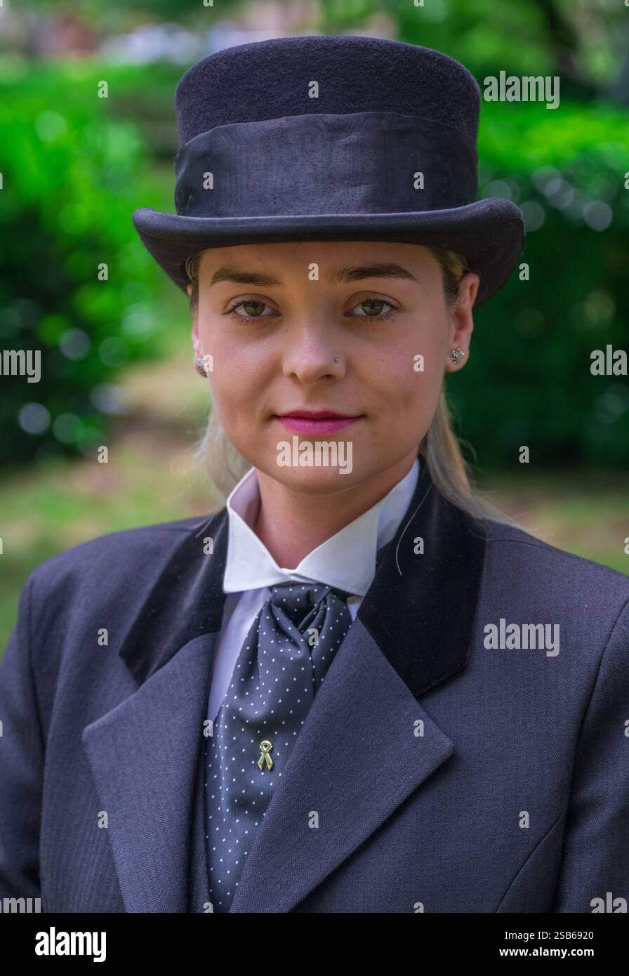 A young pretty lady funeral director in traditional attire with top hat ...