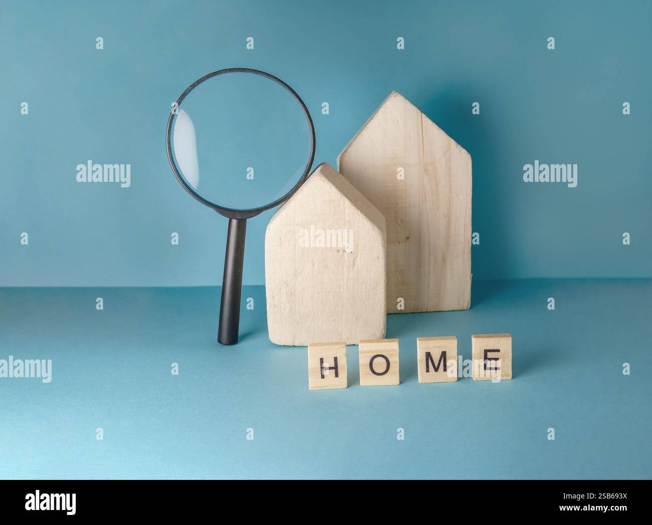 Magnifying glass is on a table with a house and some wooden blocks. The ...