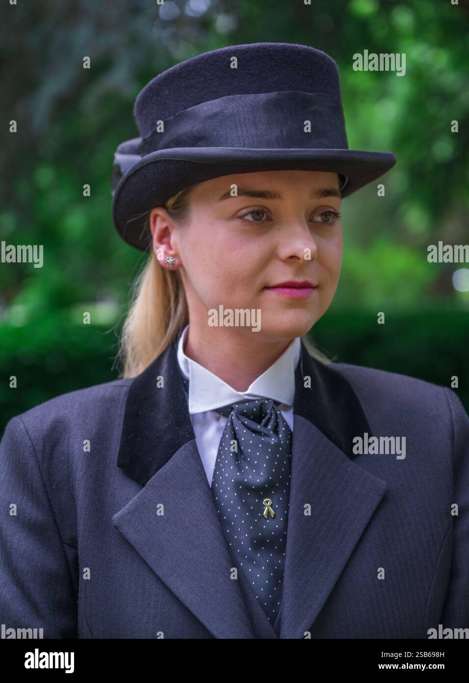A young pretty lady funeral director in traditional attire with top hat ...