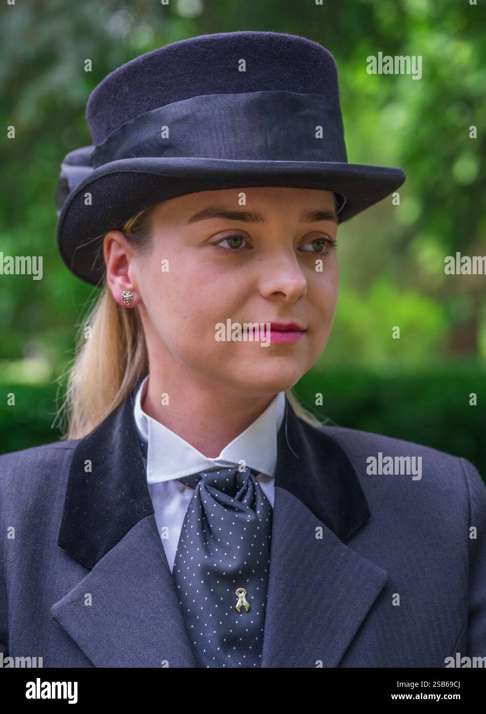 A young pretty lady funeral director in traditional attire with top hat ...
