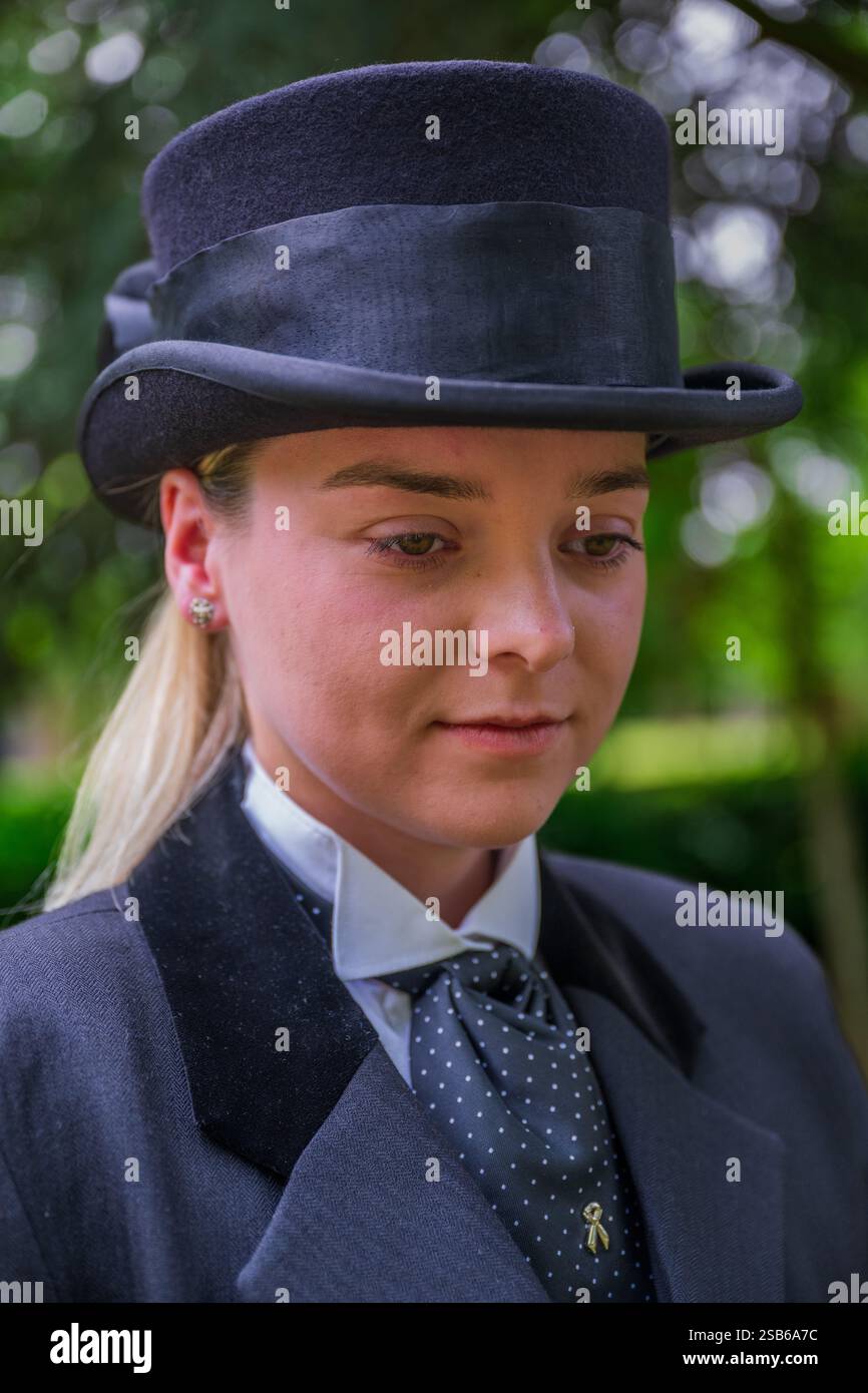 A young pretty lady funeral director in traditional attire with top hat ...