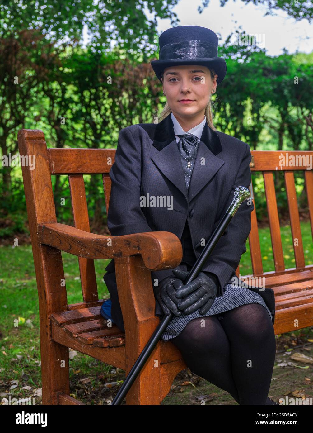 A young pretty lady funeral director in traditional attire with top hat ...