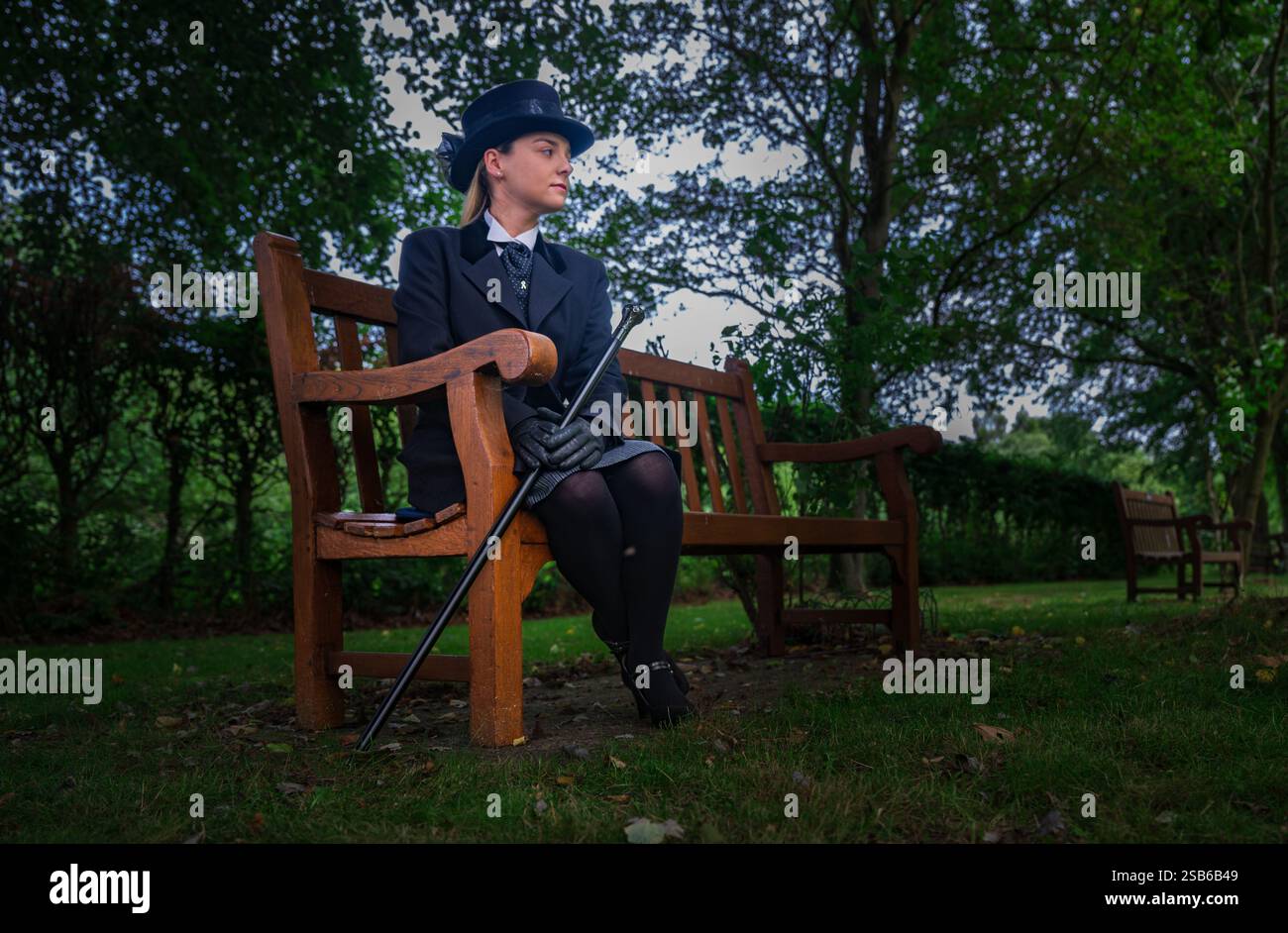 A young pretty lady funeral director in traditional attire with top hat ...
