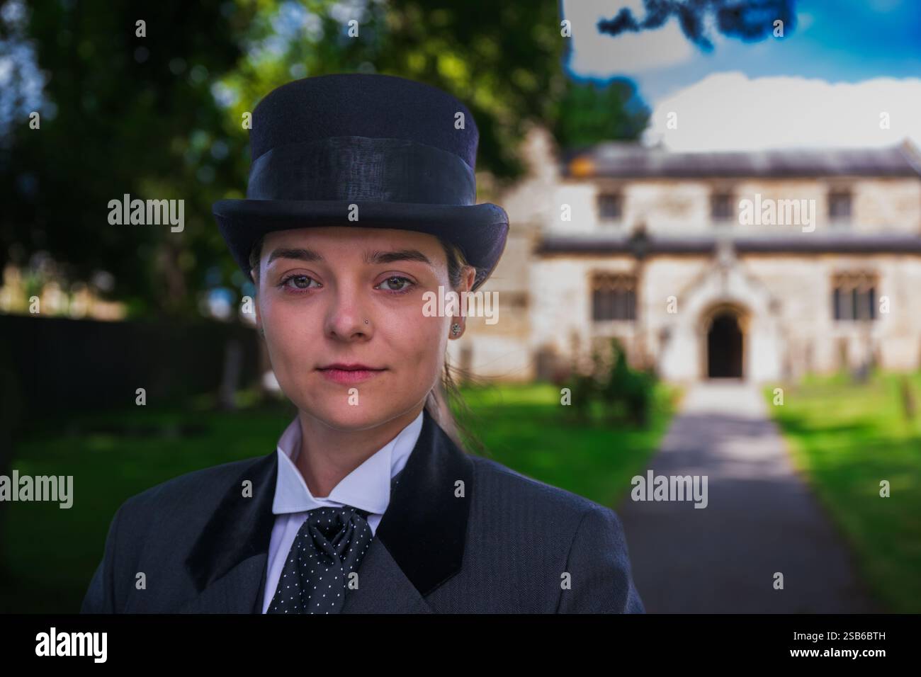 A young pretty lady funeral director in traditional attire with top hat ...