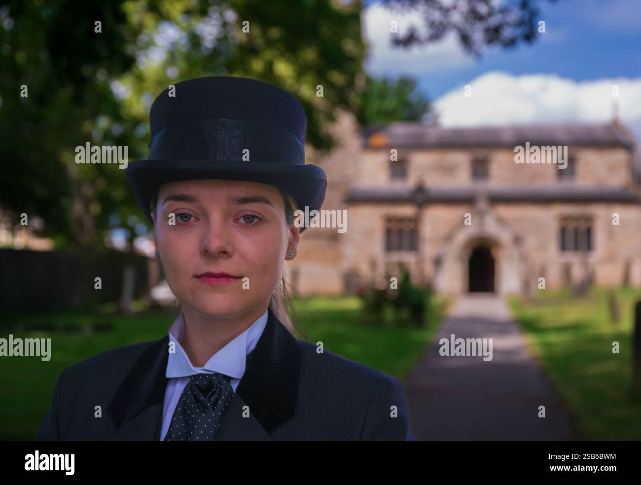 A young pretty lady funeral director in traditional attire with top hat ...