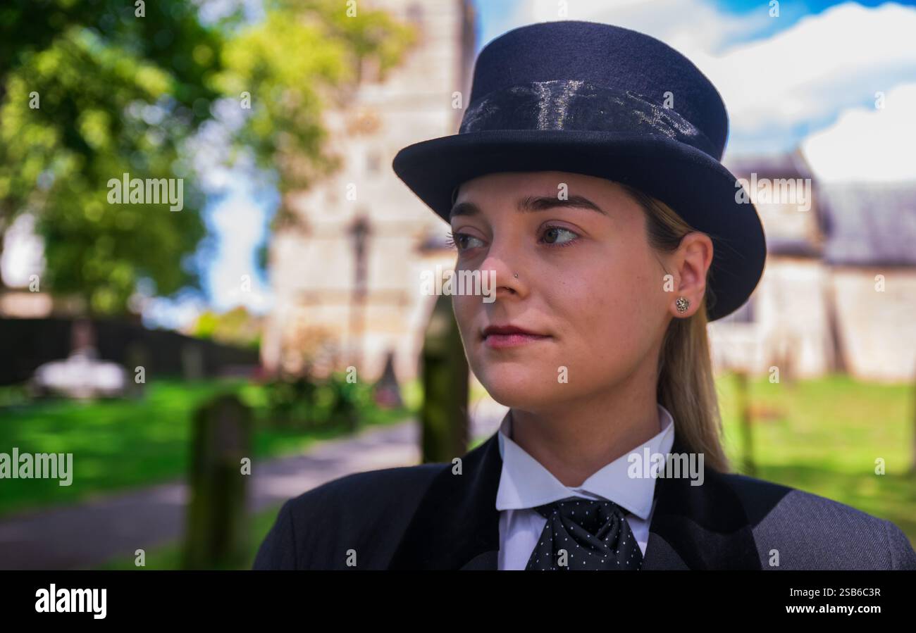 A young pretty lady funeral director in traditional attire with top hat ...