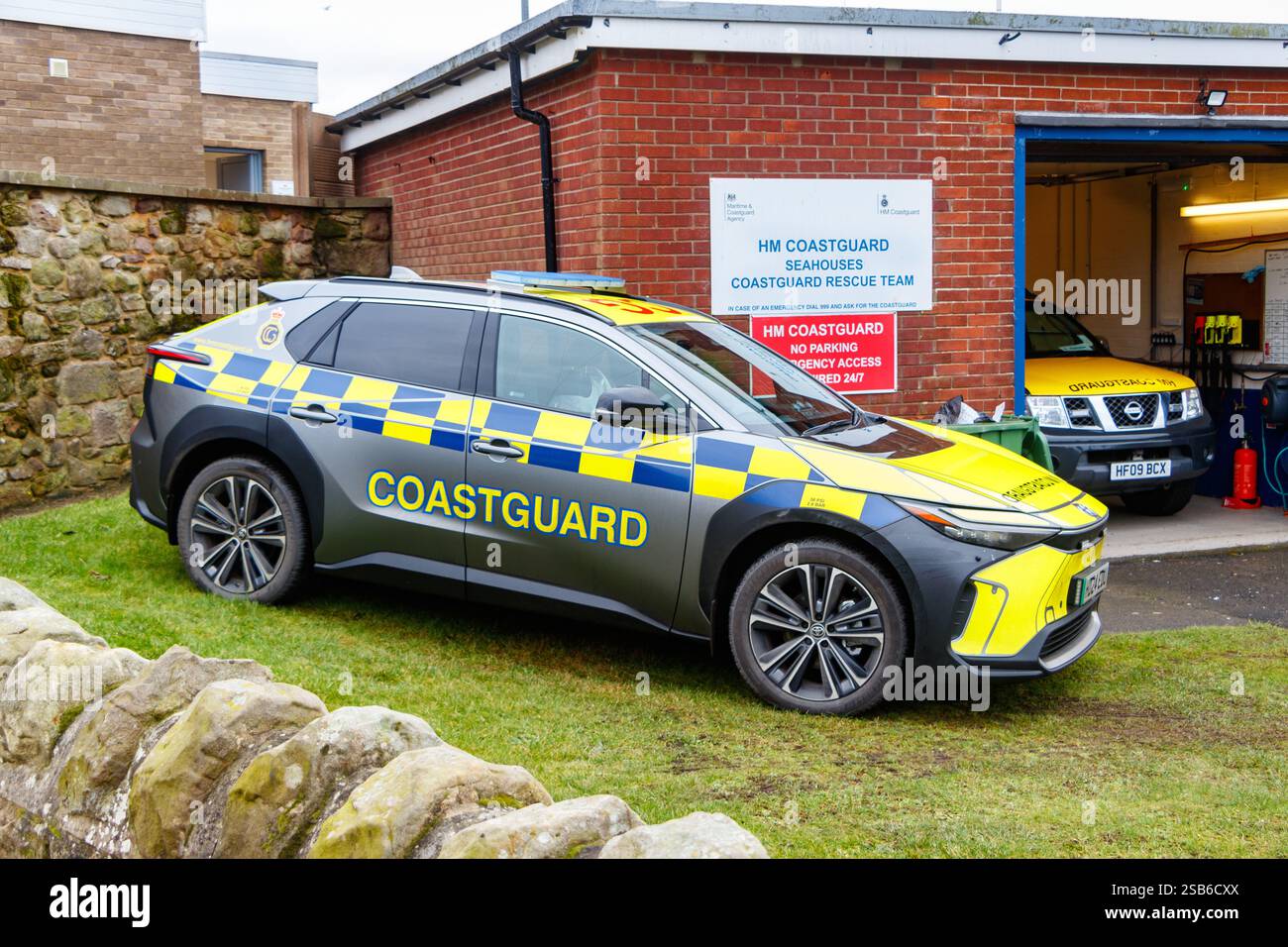 Coastguard vehicles parked at a small brick station, one inside the ...