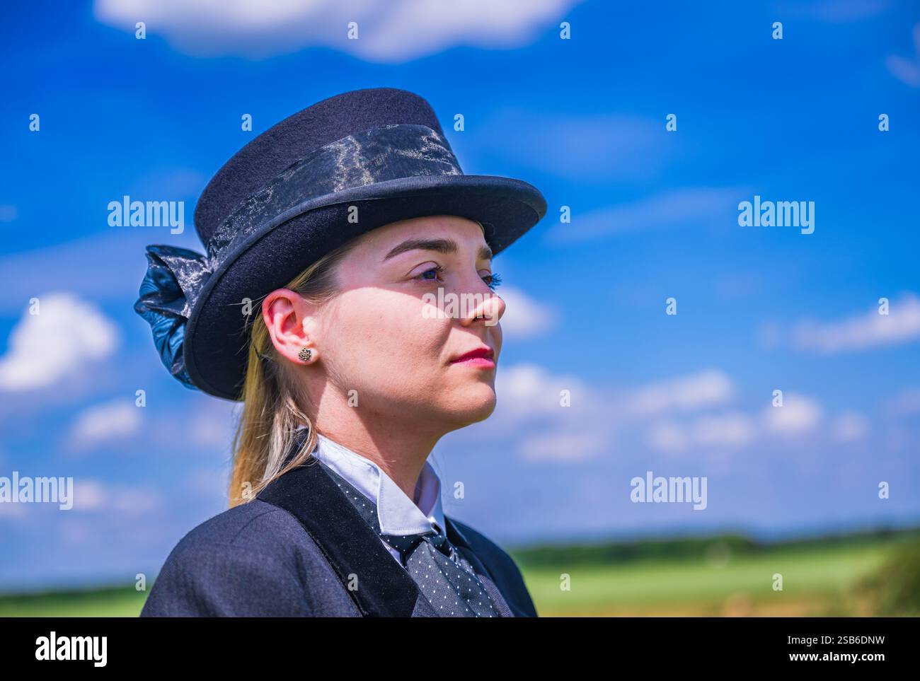 A young pretty lady funeral director in traditional attire with top hat ...