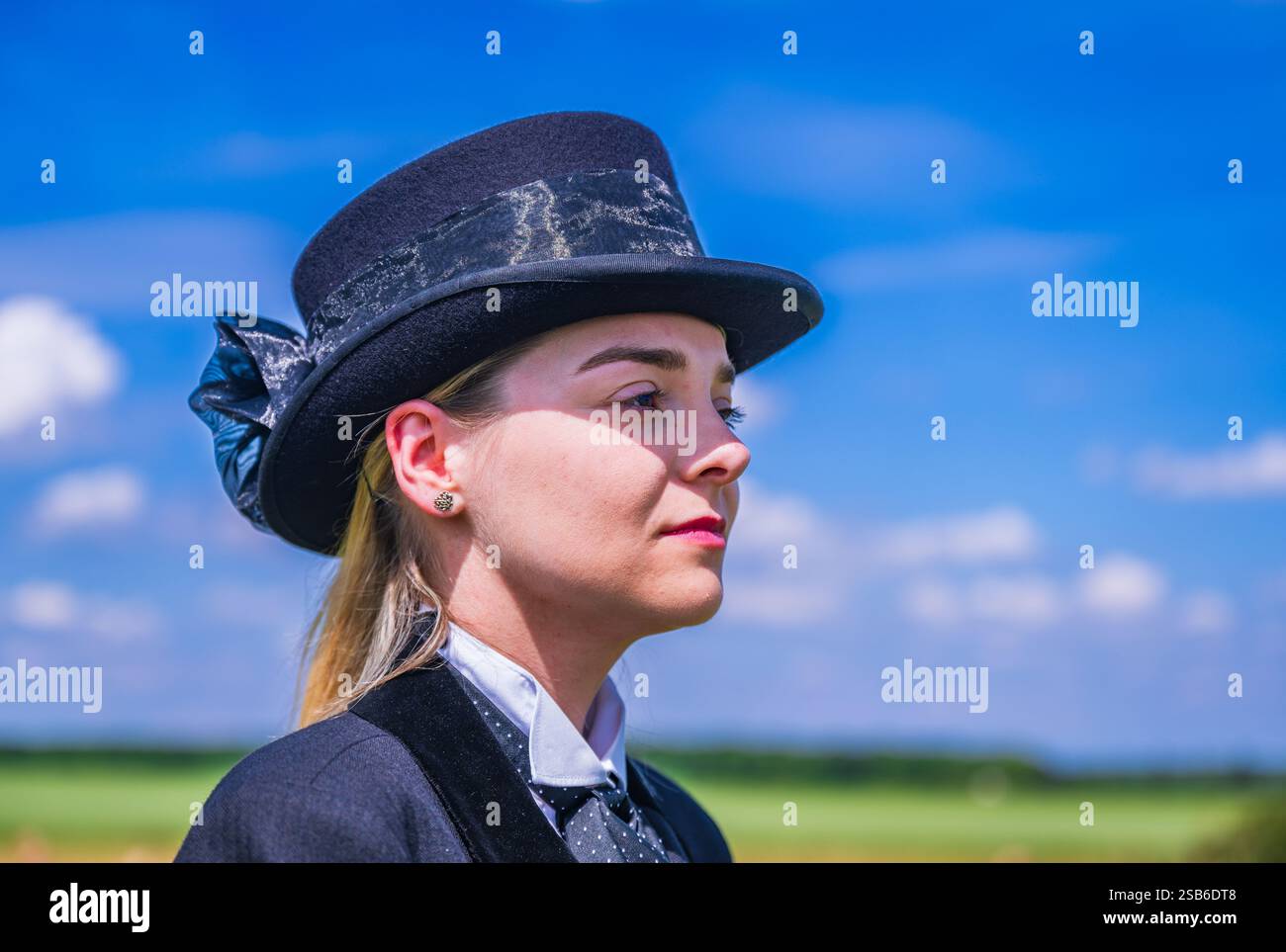 A young pretty lady funeral director in traditional attire with top hat ...