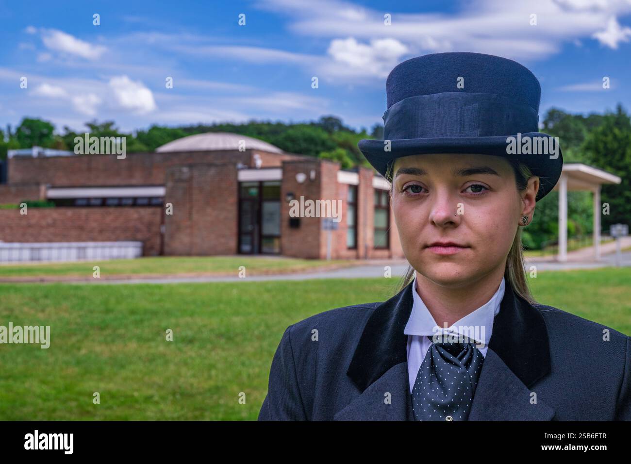 A young pretty lady funeral director in traditional attire with top hat ...