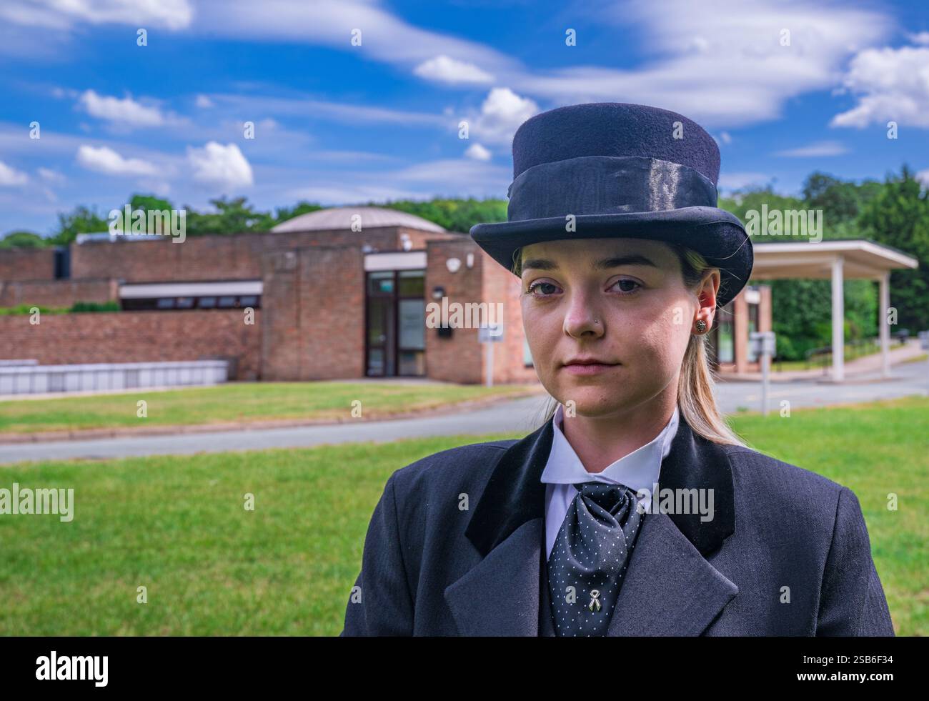 A young pretty lady funeral director in traditional attire with top hat ...