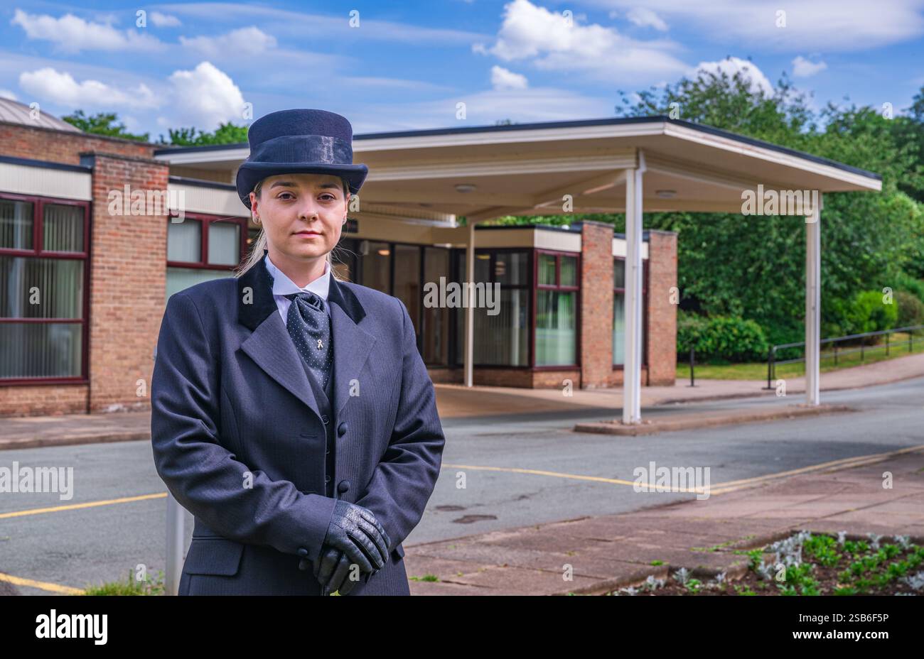 A young pretty lady funeral director in traditional attire with top hat ...