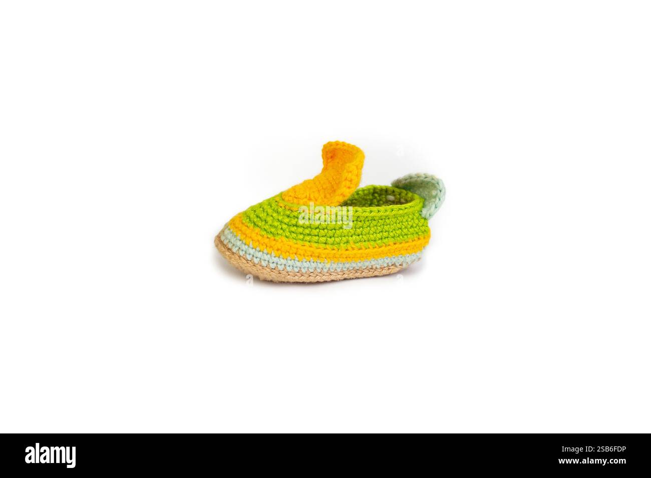 one very small crochet shoe with green and yellow thread, isolated on ...
