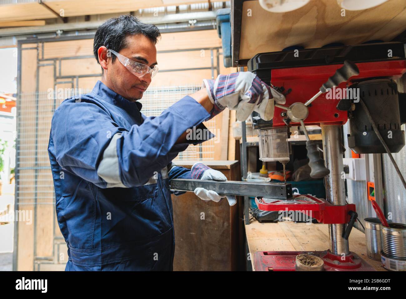 Latin worker drilling metal in workshop using bench drill press Stock ...