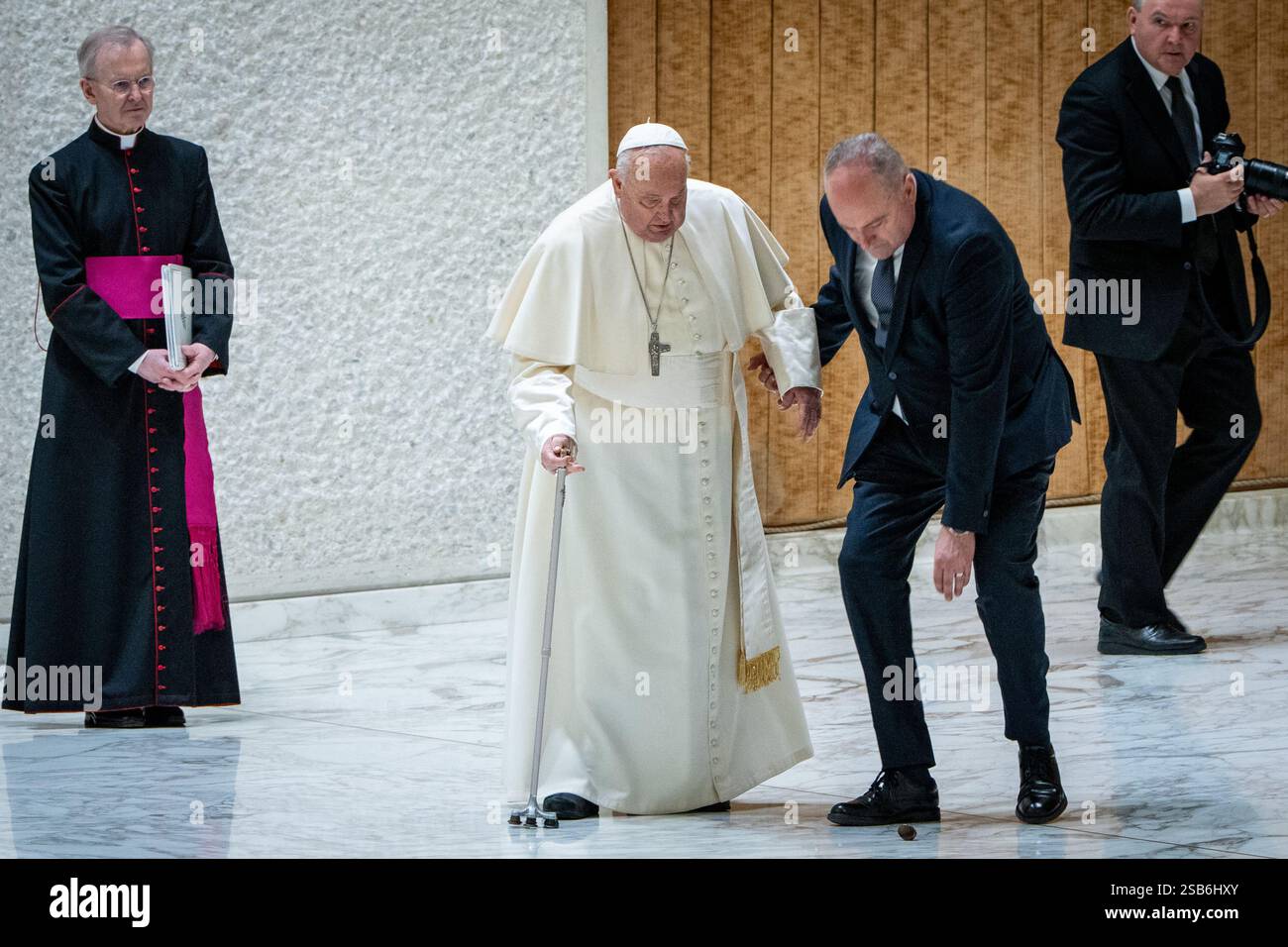 Pope Francis' aide leans down to pick up the handle of Pope's walking ...