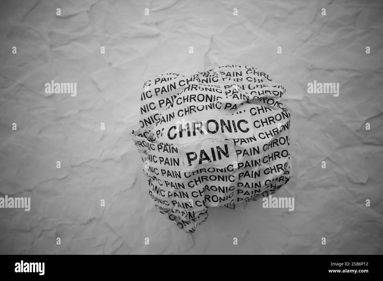 Crumpled paper ball with words Chronic Pain on torn white paper pieces ...