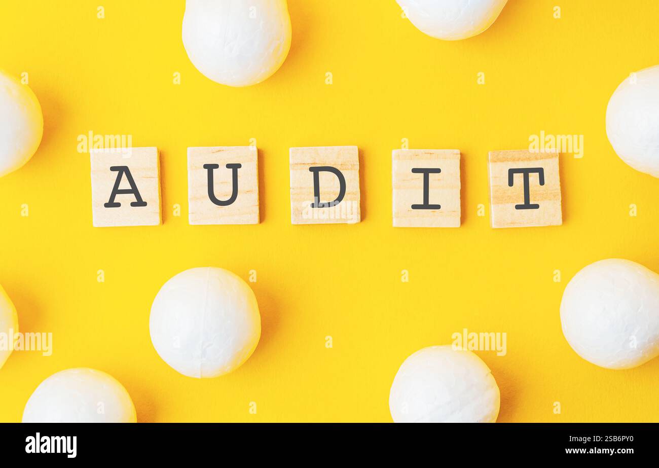 Yellow background with white balls. The word audit is written in black ...